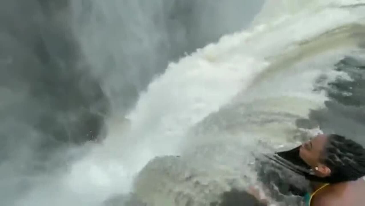 Woman leans over edge of 360-feet-tall Victoria Falls in breathtaking ...